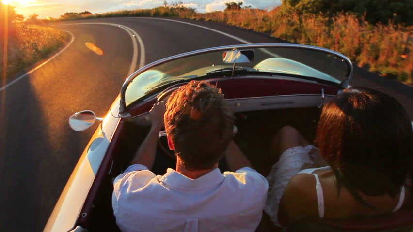 Couple Driving Convertible Car. Steadicam Shot With Flare Into Sunset ...