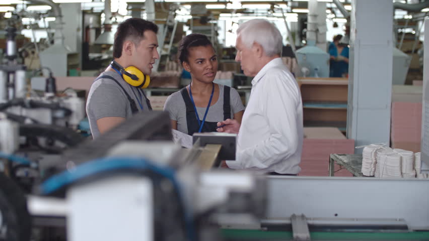Stock video of elderly factory supervisor discussing work with ...