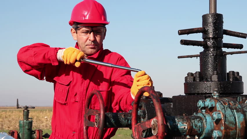 Refinery Worker And Pipelines. Worker Wearing Red Overalls And Hardhat ...