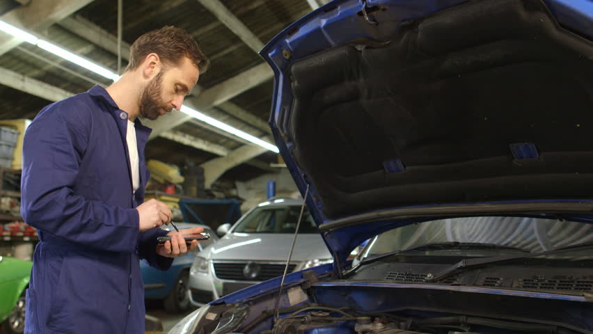 Male Tutor Instructing Female College Student In Car Mechanics Class As ...